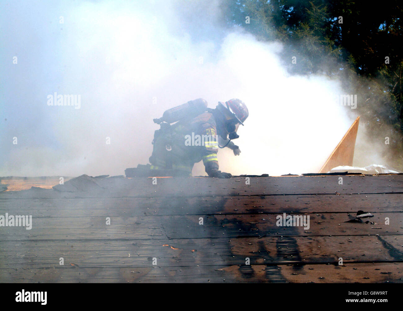 Firefighter encased in smoke on roof of house Stock Photo - Alamy