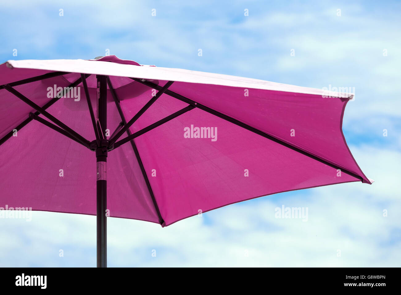 Dark pink parasol on blue cloudy sky Stock Photo - Alamy