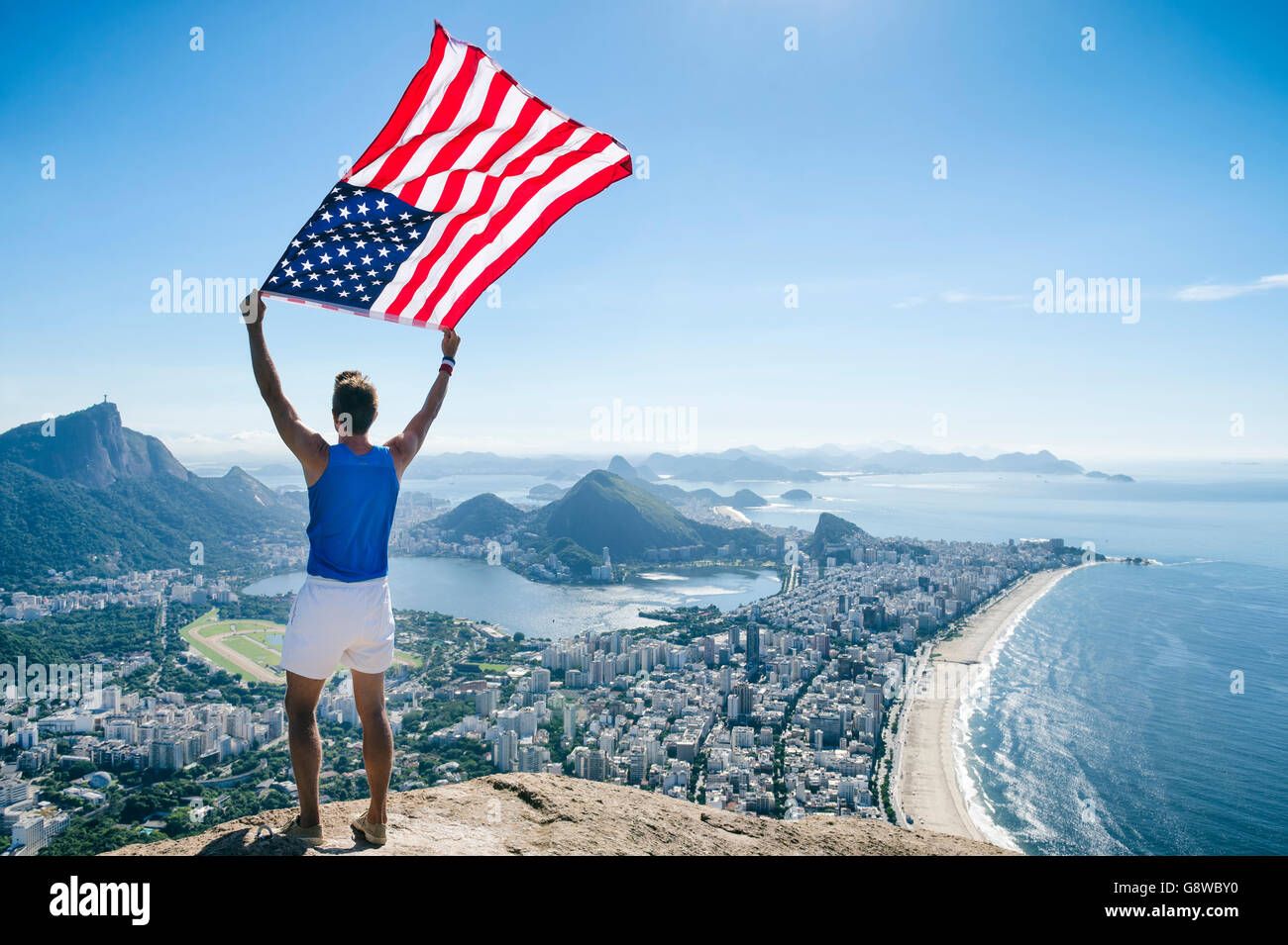 Athlete stands holding an American flag at a bright overlook of the ...
