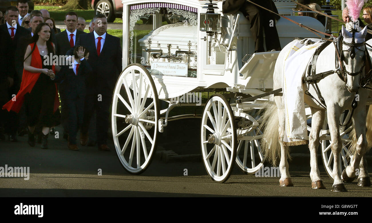 Mourners walk behind a horse drawn hearse carrying the coffin of 15 ...