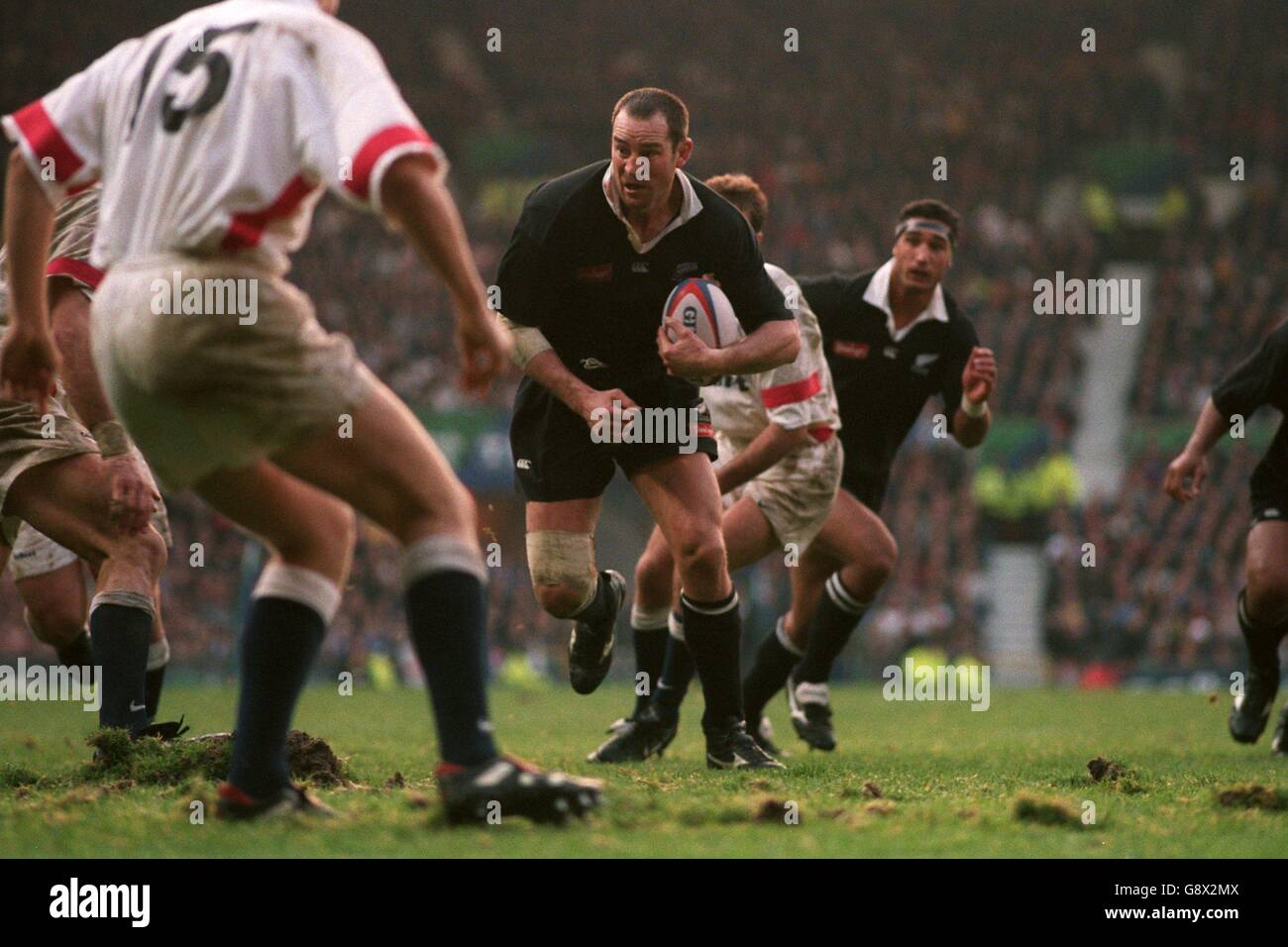 Robin Brooke of New Zealand (centre) storms through the England defence ...