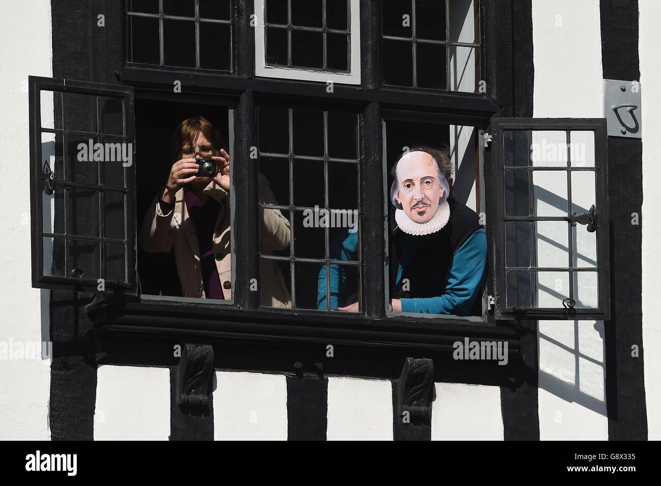 A man peers out of a window wearing a William Shakespeare mask during ...