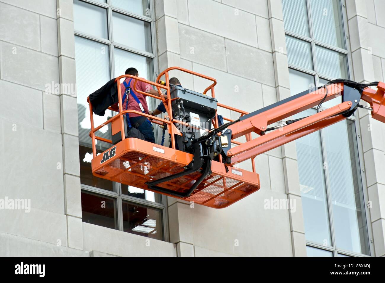Two men up in the air on a lift washing the windows of a building in DC ...