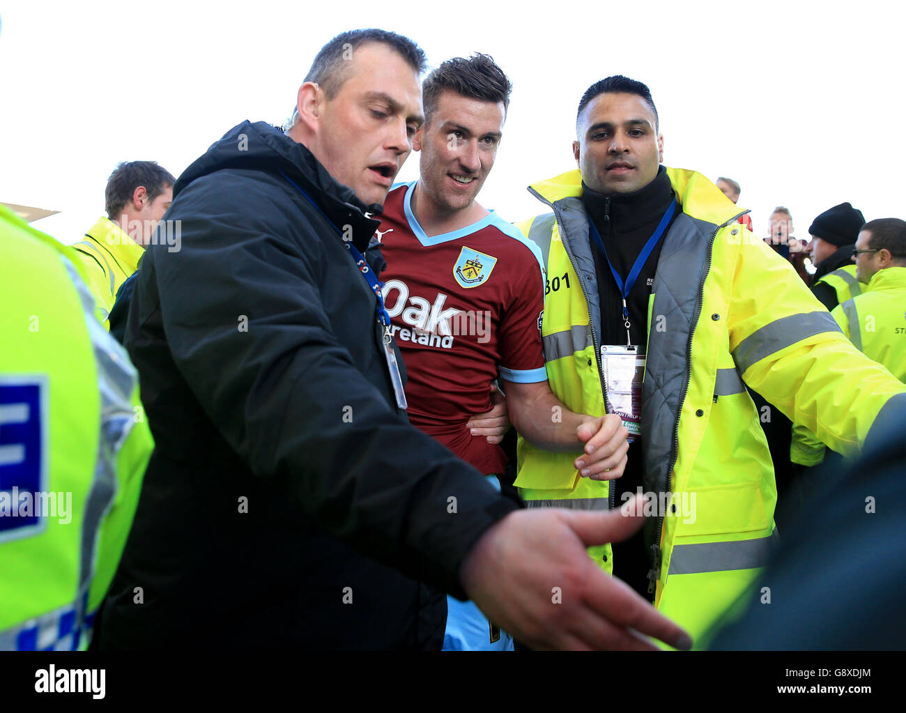Burnley's David Jones is helped off the pitch by security as fans ...