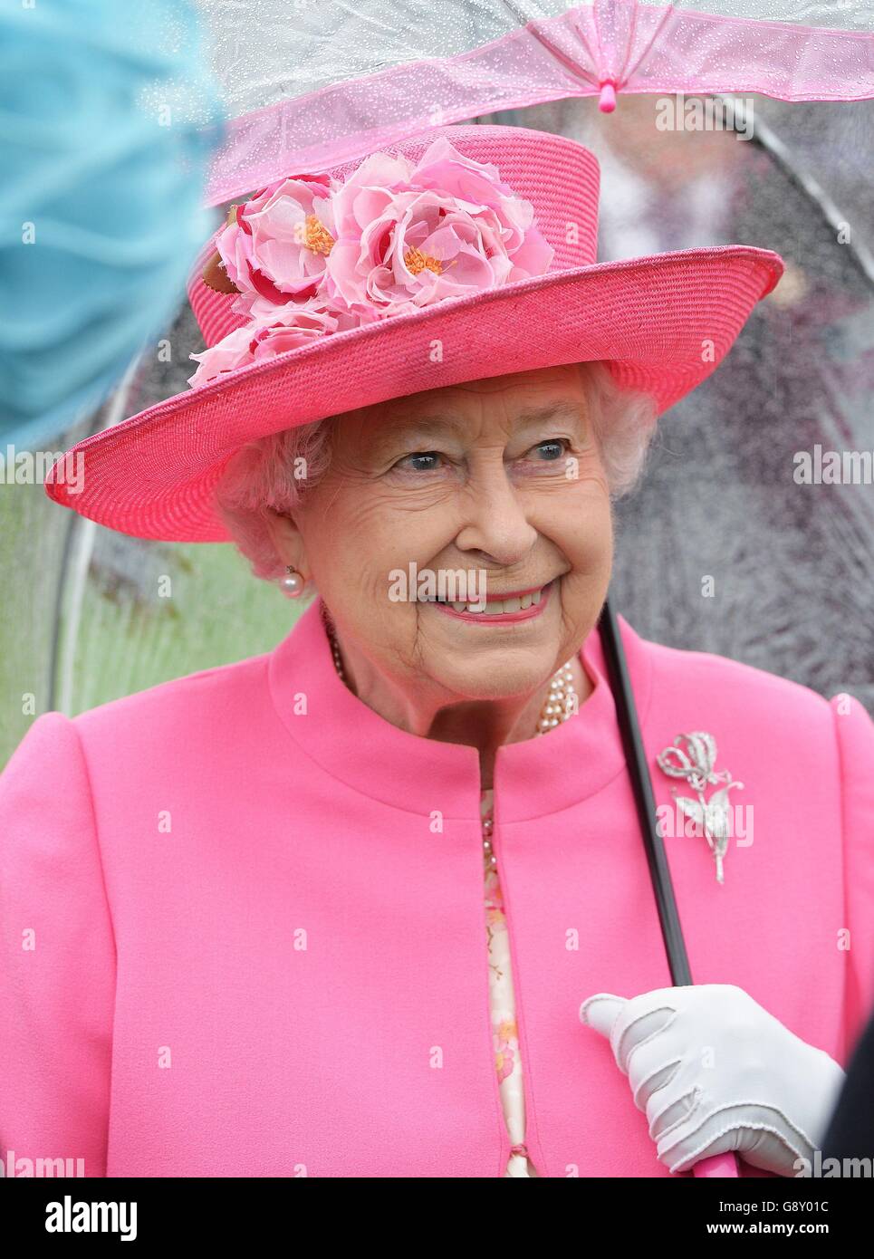 Queen Elizabeth II shelters from the rain under an umbrella in the ...