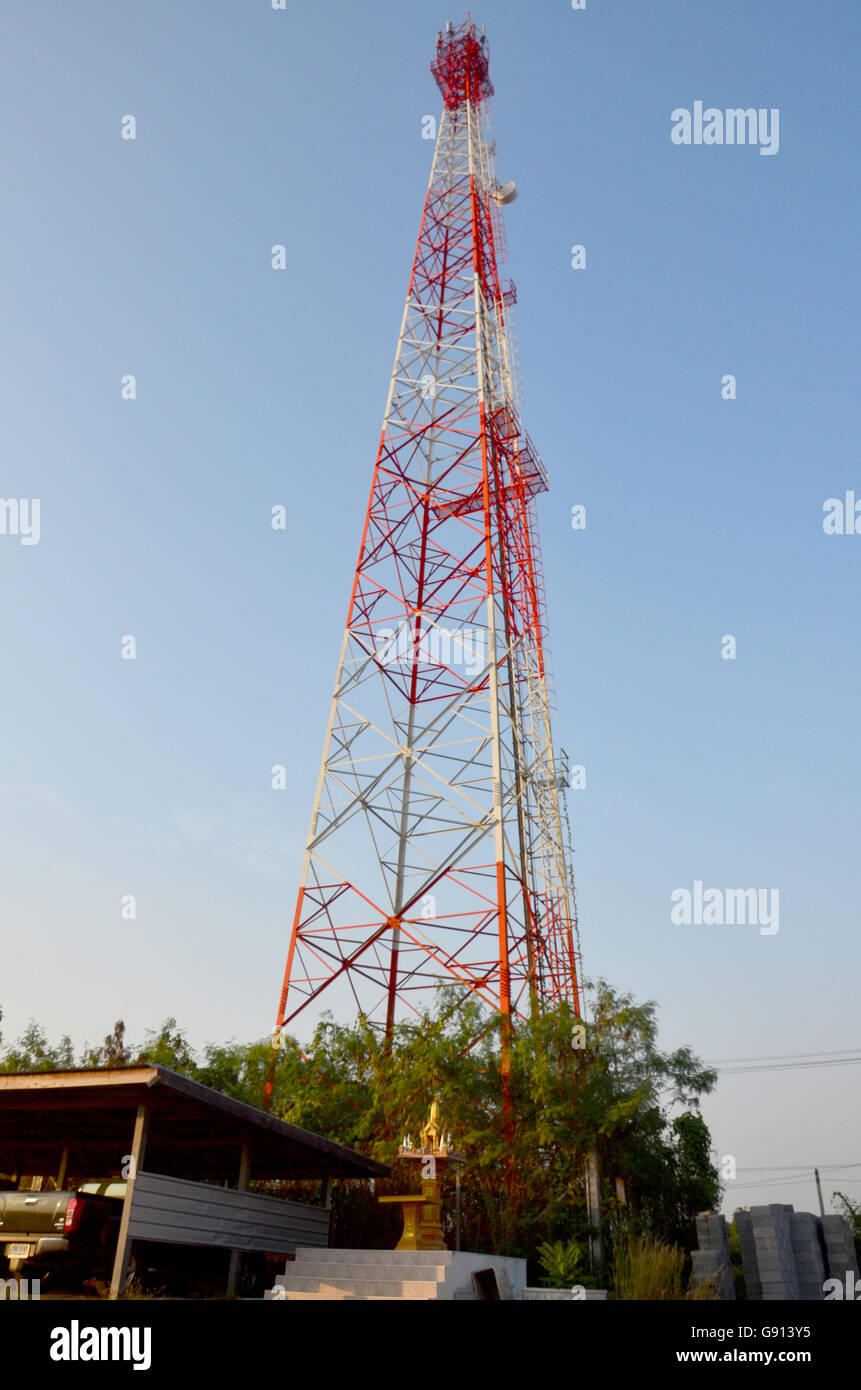Red and white telecommunication tower with a lot of different antennas ...