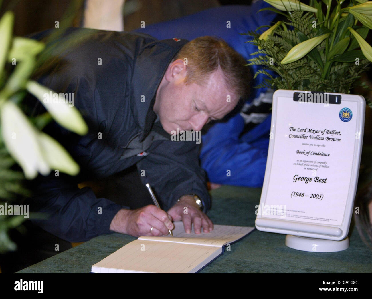 A mourner signs a book of condolence for football legend George Best at ...