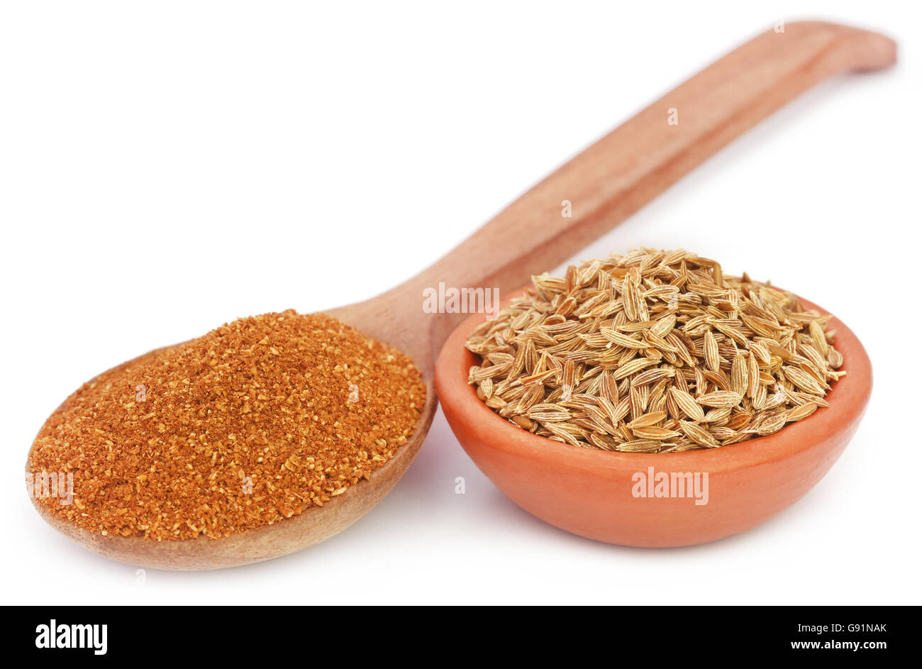 Crushed cumin with whole ones over white background Stock Photo - Alamy