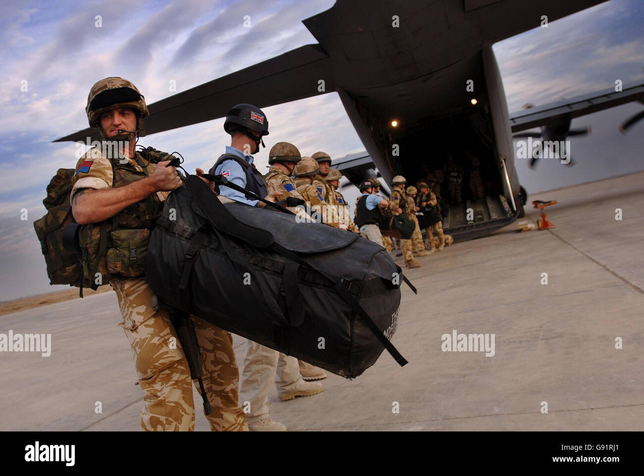 British soldiers unload an RAF Hercules aircraft at a landing strip ...