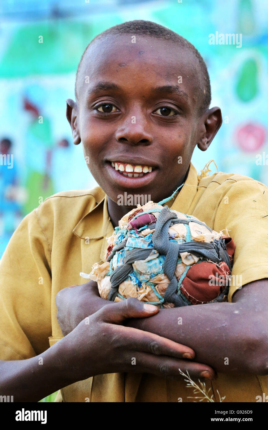 Young boy (12 years) with his self-made football made of fabric scraps ...