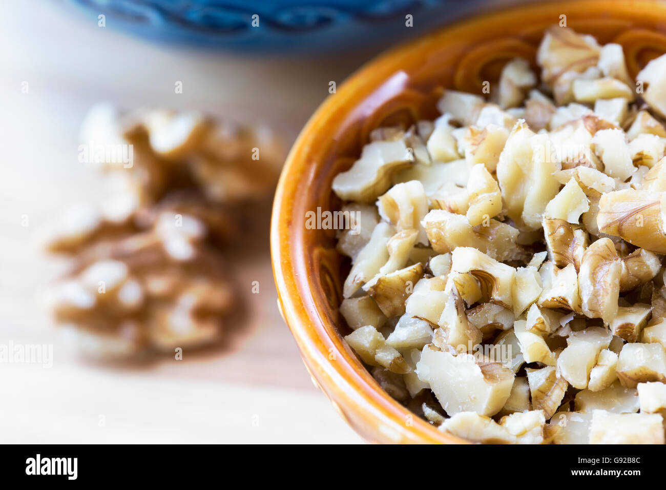Chopped walnut pieces in an orange bowl on table Stock Photo - Alamy