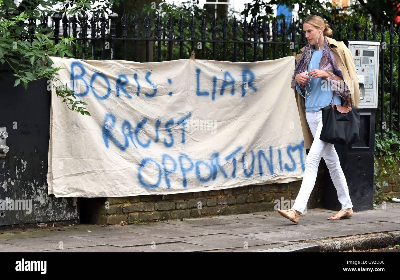 A woman walks past a banner put up by protesters opposite the home of ...