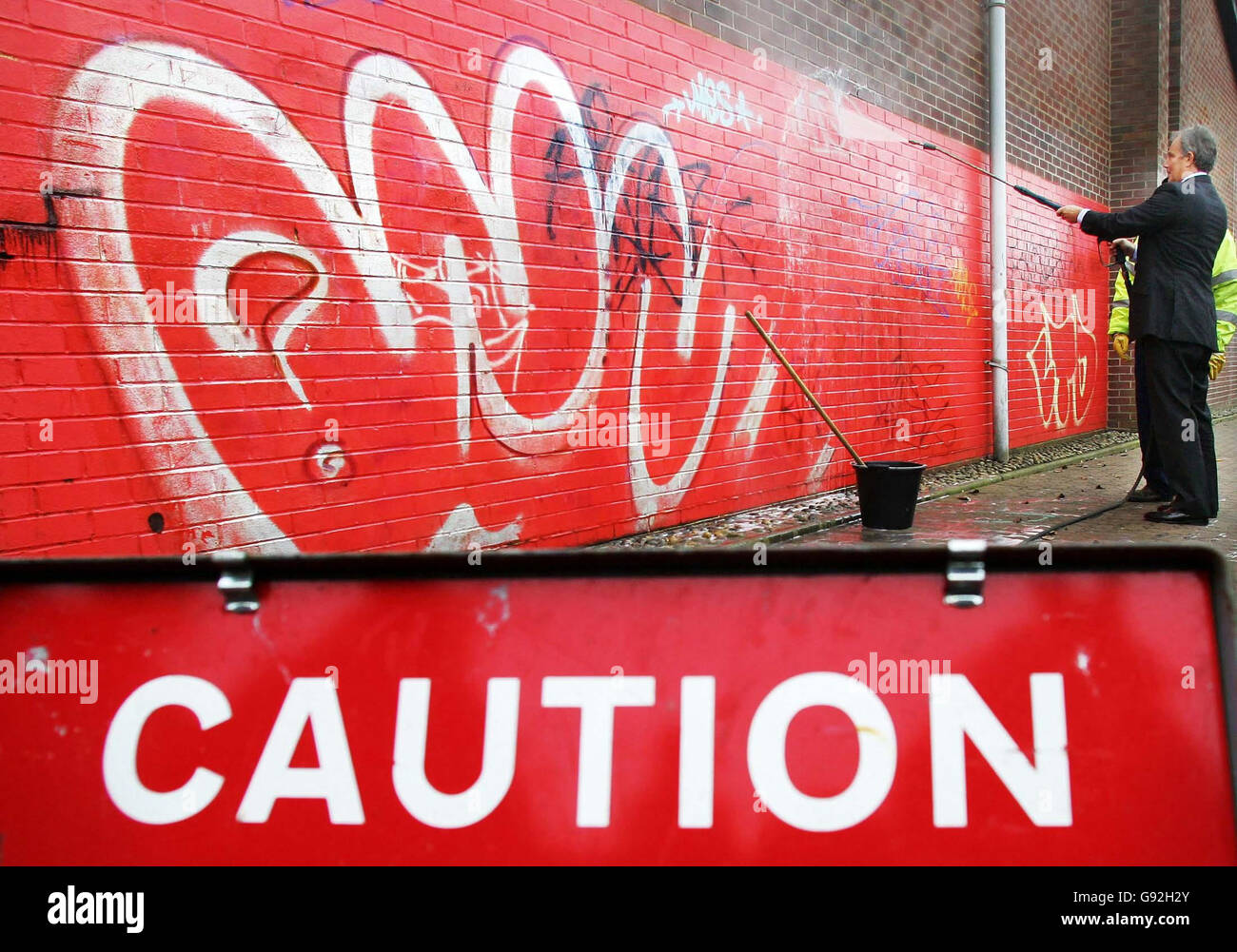 British Prime Minister Tony Blair cleans graffiti from a wall with a ...