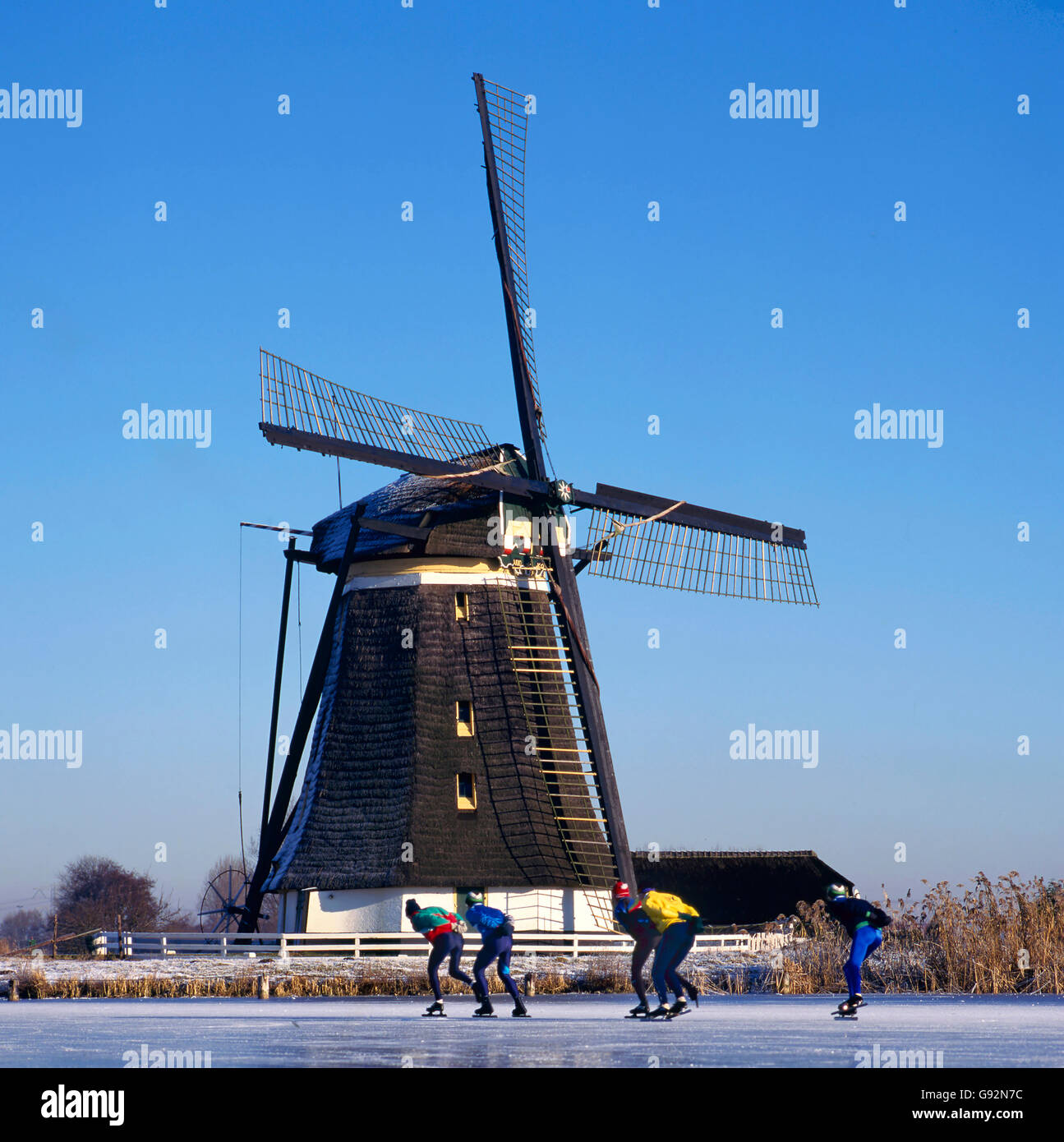 Windmill and skaters at the foreground at a Dutch frozen river Stock ...