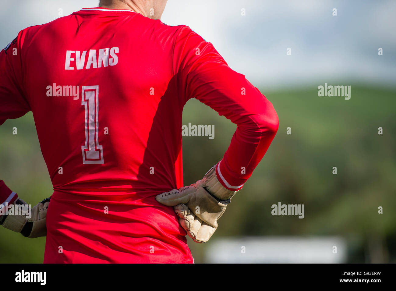 Rear view of a Goalkeeper wearing a red Evans No 1 shirt standing in ...