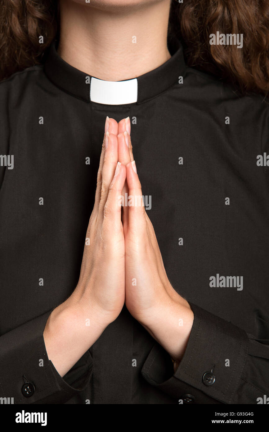 Priest wearing a clerical collar and with hands clasped together ...