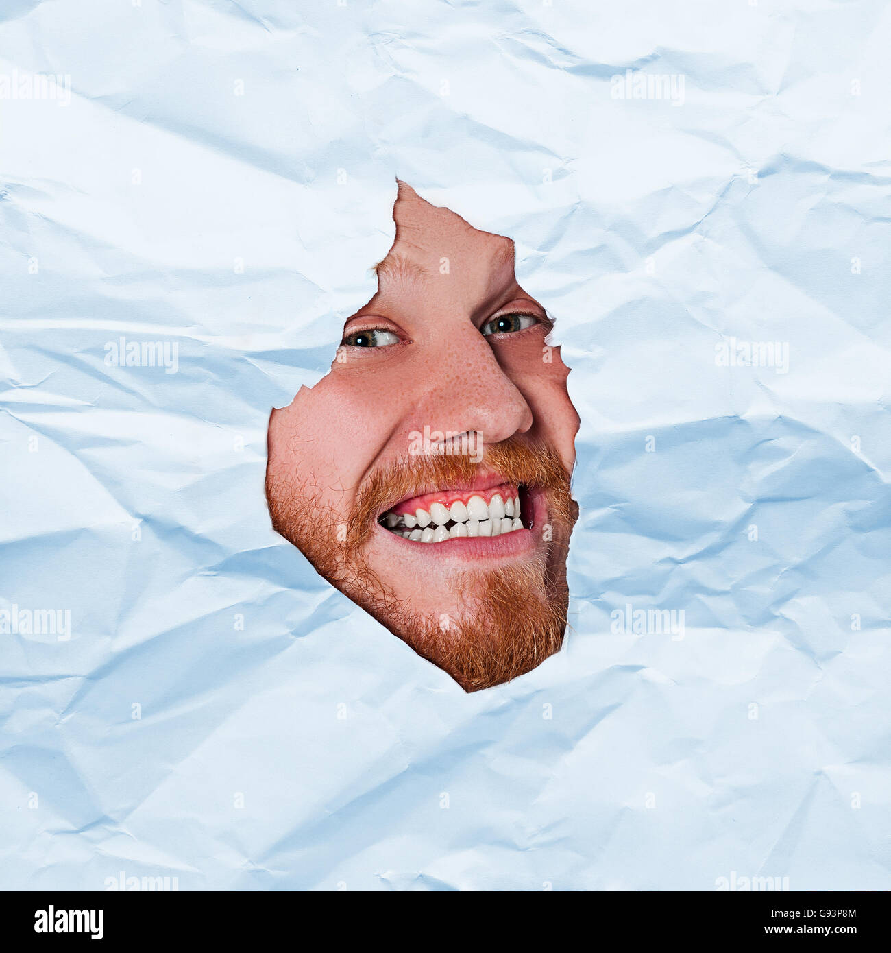 Young man looking through paper rip Stock Photo - Alamy