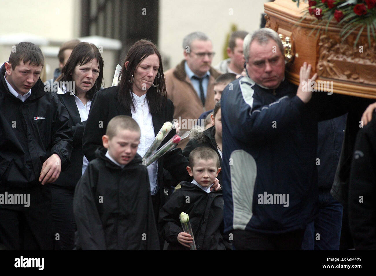 Aine Devlin (carrying roses), wife of Gerard Devlin, walks behind his ...