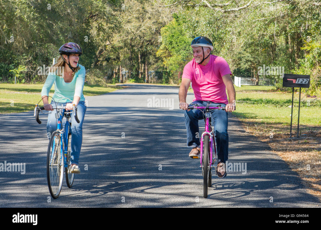 couple aged 40s and 50s riding bike at home in neighborhood safety ...