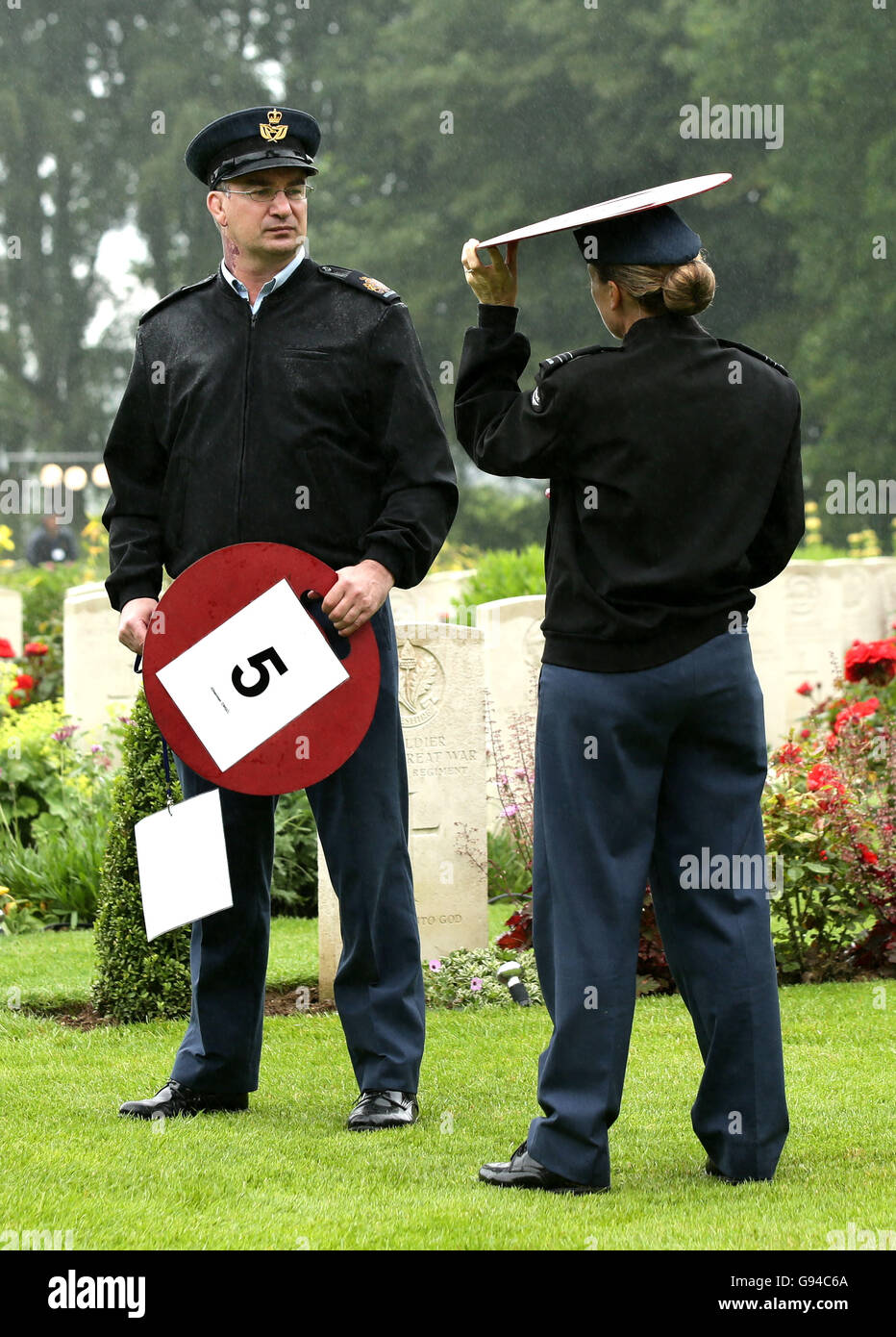 A soldier uses a rehearsal wreath to shelter from the rain, ahead of ...