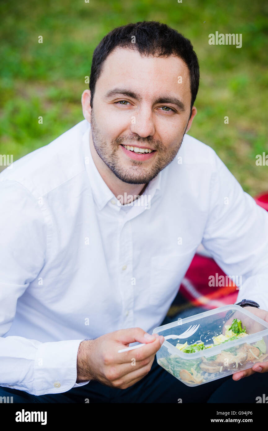 young business man enjoying food which he brought in a lunch box from ...