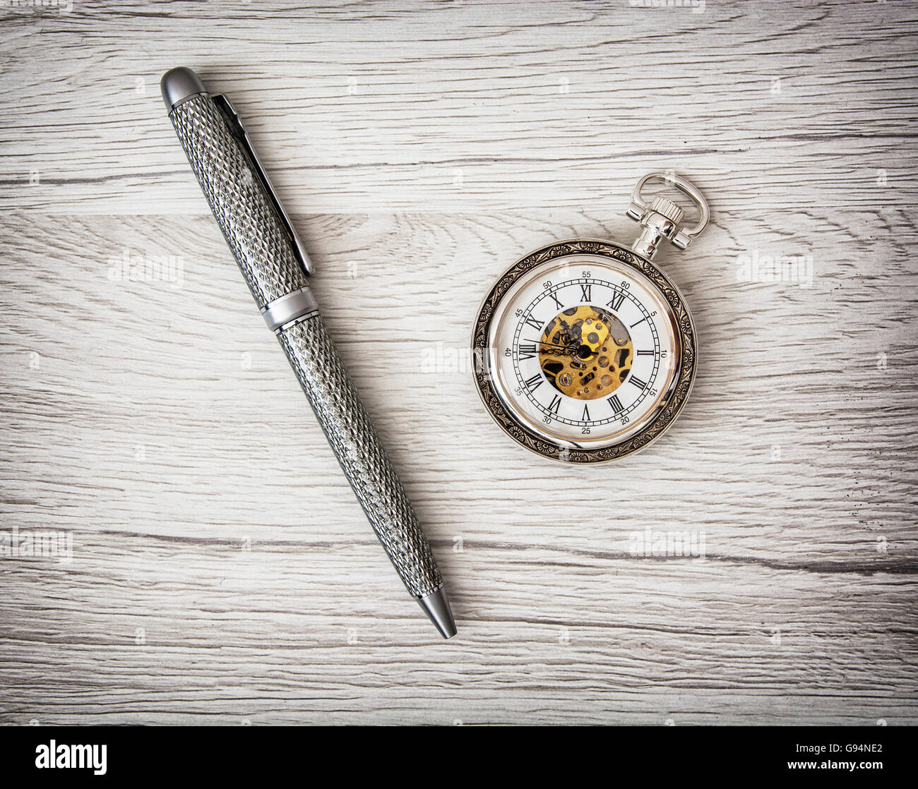 Retro pocket watch and exclusive pen on the wooden texture. Symbolic ...