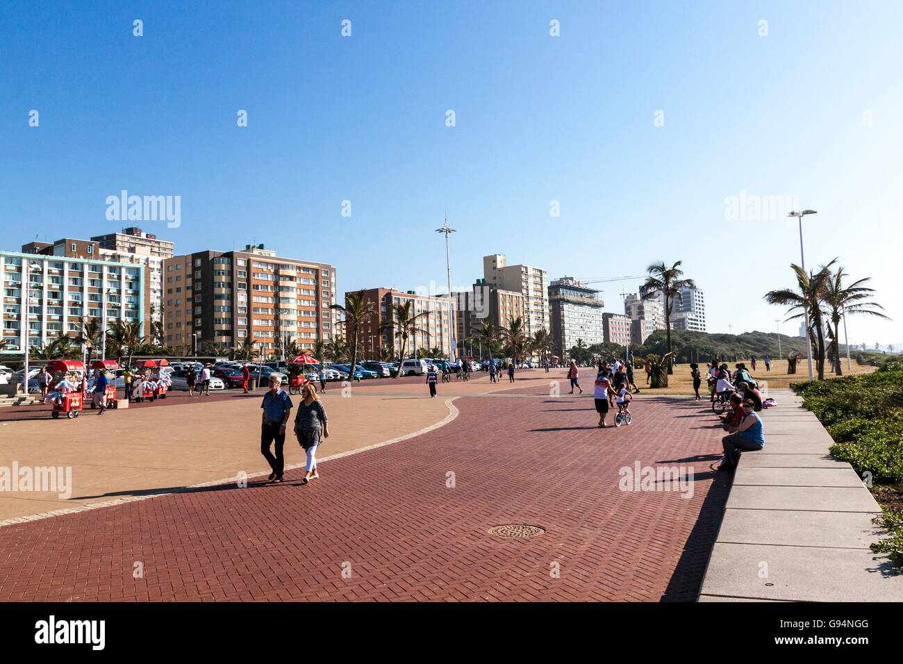 People walking along paved promenade on beach front against city ...