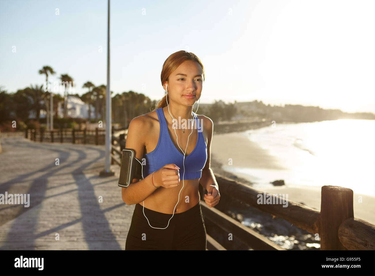 Waist up portrait of a young adult jogger running on the beach in ...