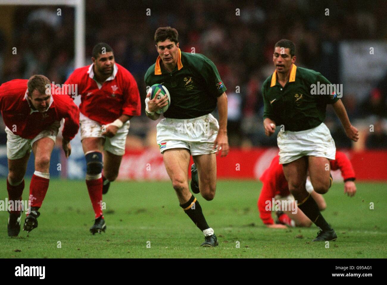 Henry Honiball of South Africa (centre) runs away from the Wales ...