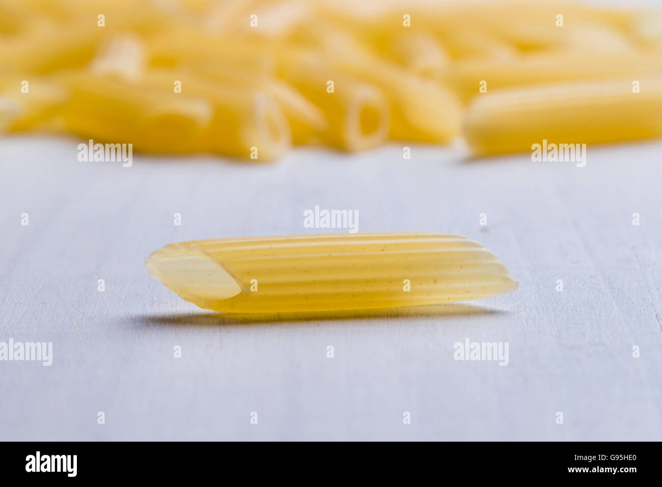 raw uncooked penne pasta on white table Stock Photo - Alamy