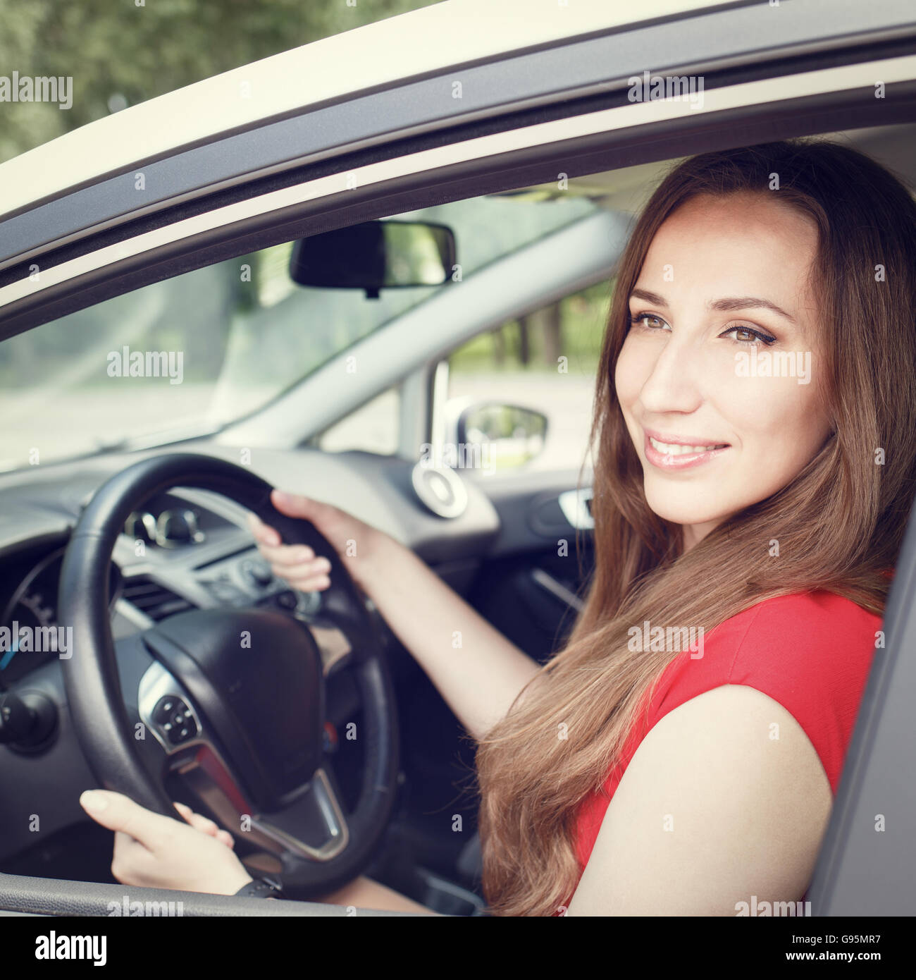 Young lady in red dress driving a car. Driving school background Stock ...