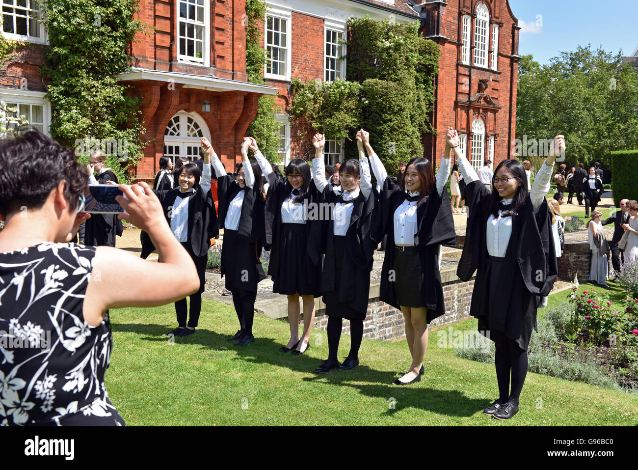 Smiling students jump into the air to celebrate graduation at Cambridge ...