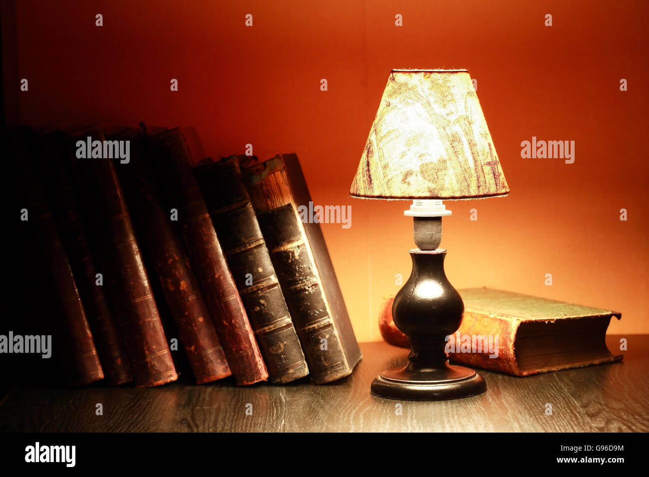 Glowing vintage table lamp near stack of old books Stock Photo - Alamy