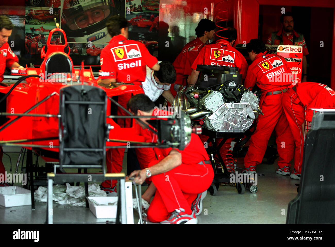 The Ferrari mechanics work hard in the pit garage preparing the cars ...