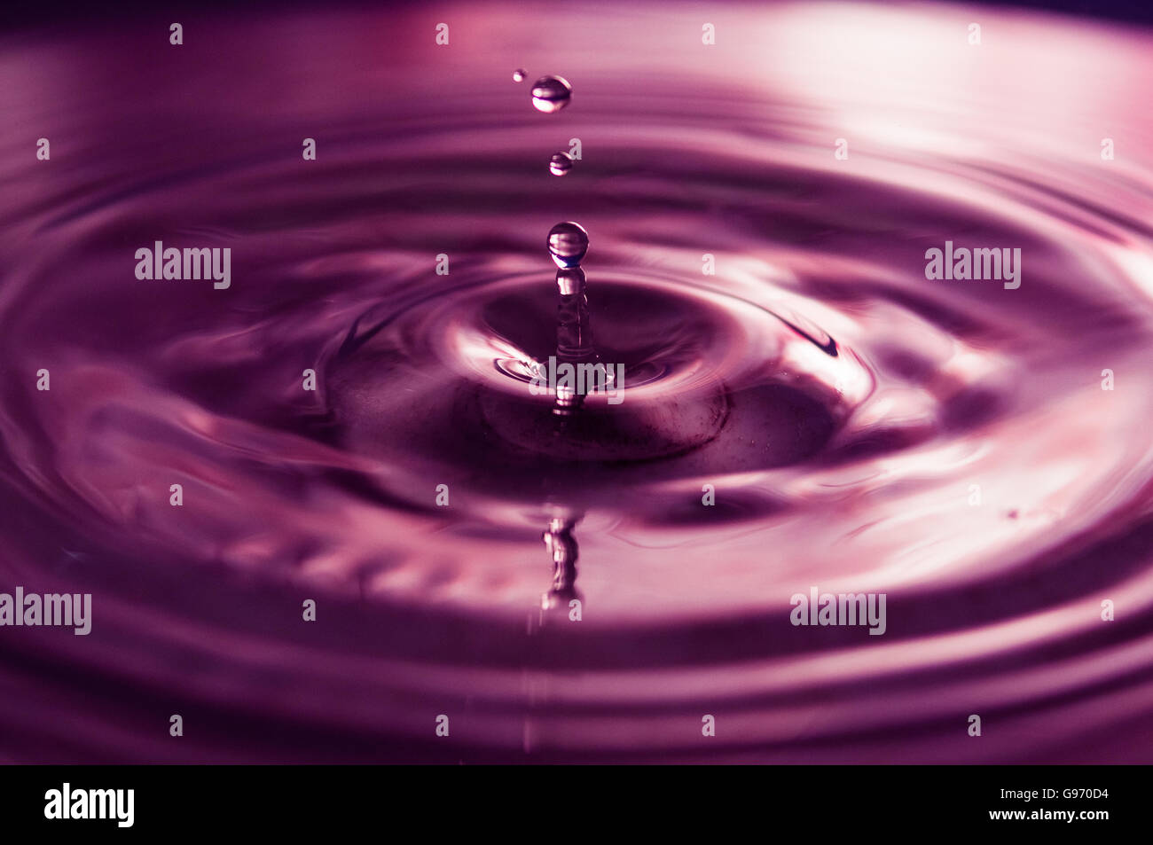 Macro photo of water drops falling into a pool of water, causing a ...