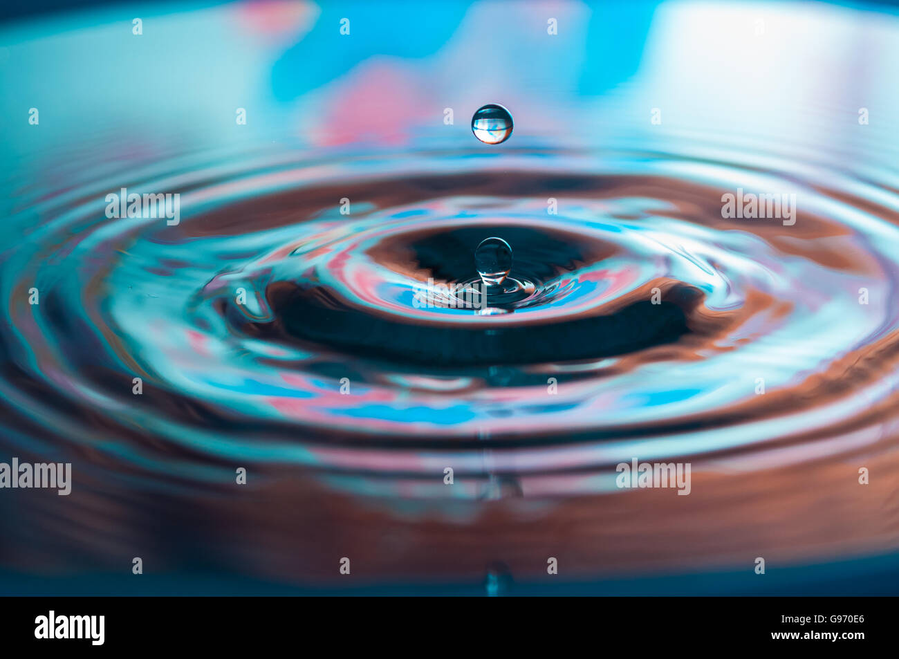 Macro photo of water drops falling into a pool of water, causing a ...