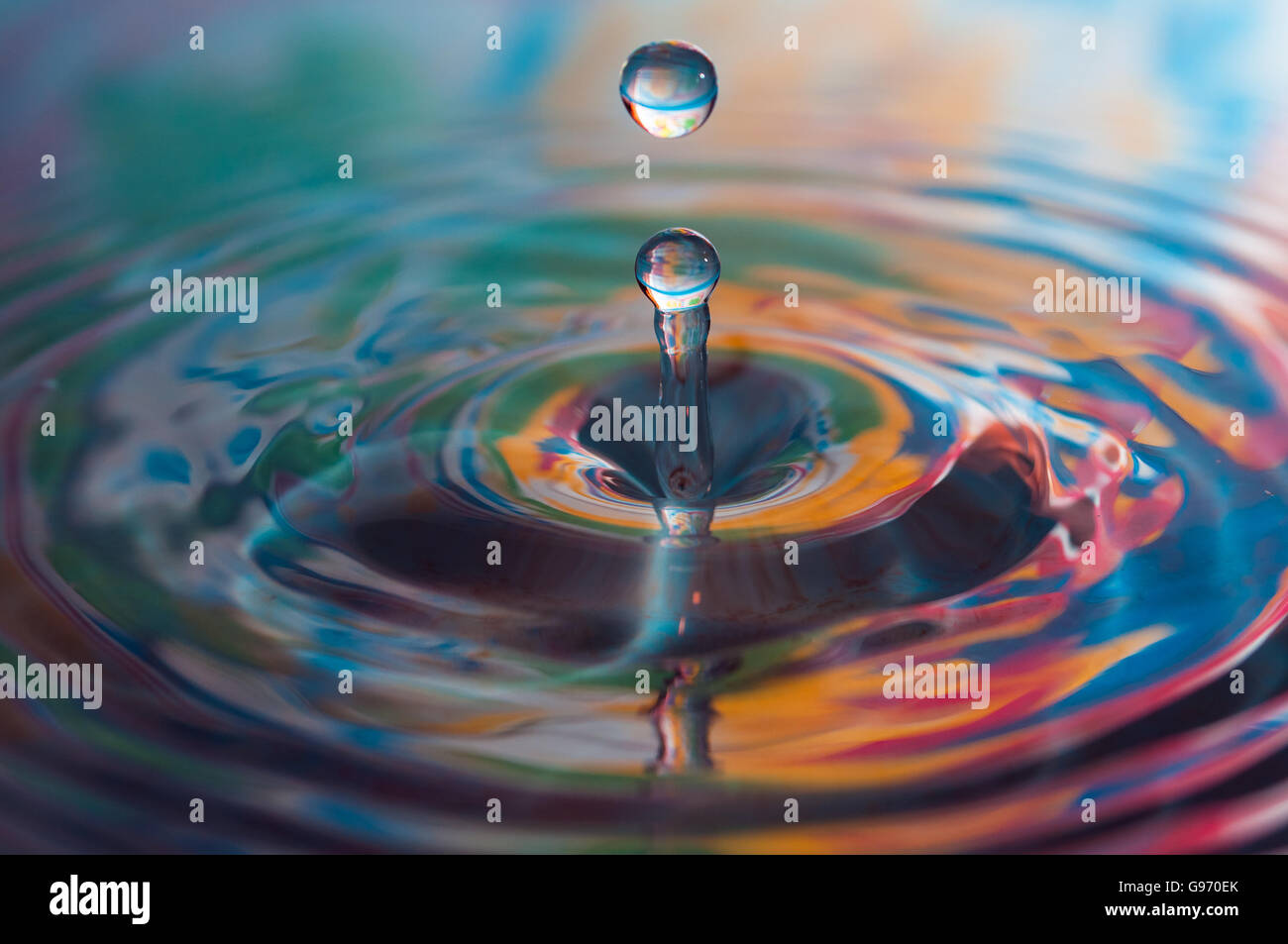 Macro photo of water drops falling into a pool of water, causing a ...