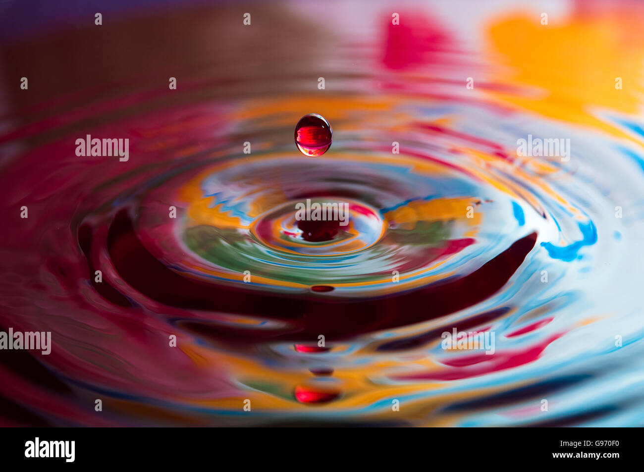 Macro photo of water drops falling into a pool of water, causing a ...