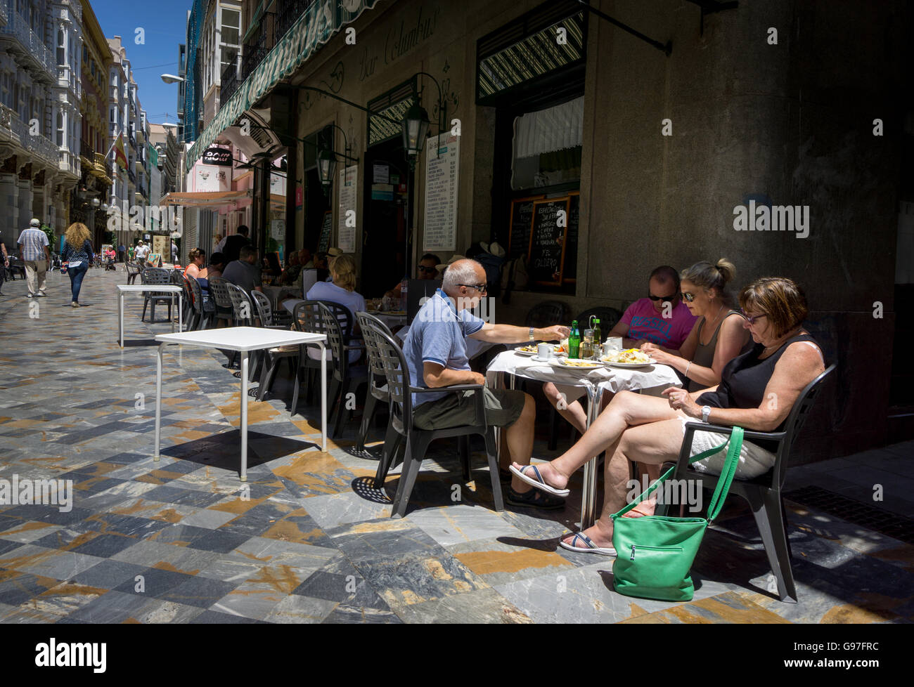 Tourists in relaxed mood, eating outside in a sunny pedestrianised ...