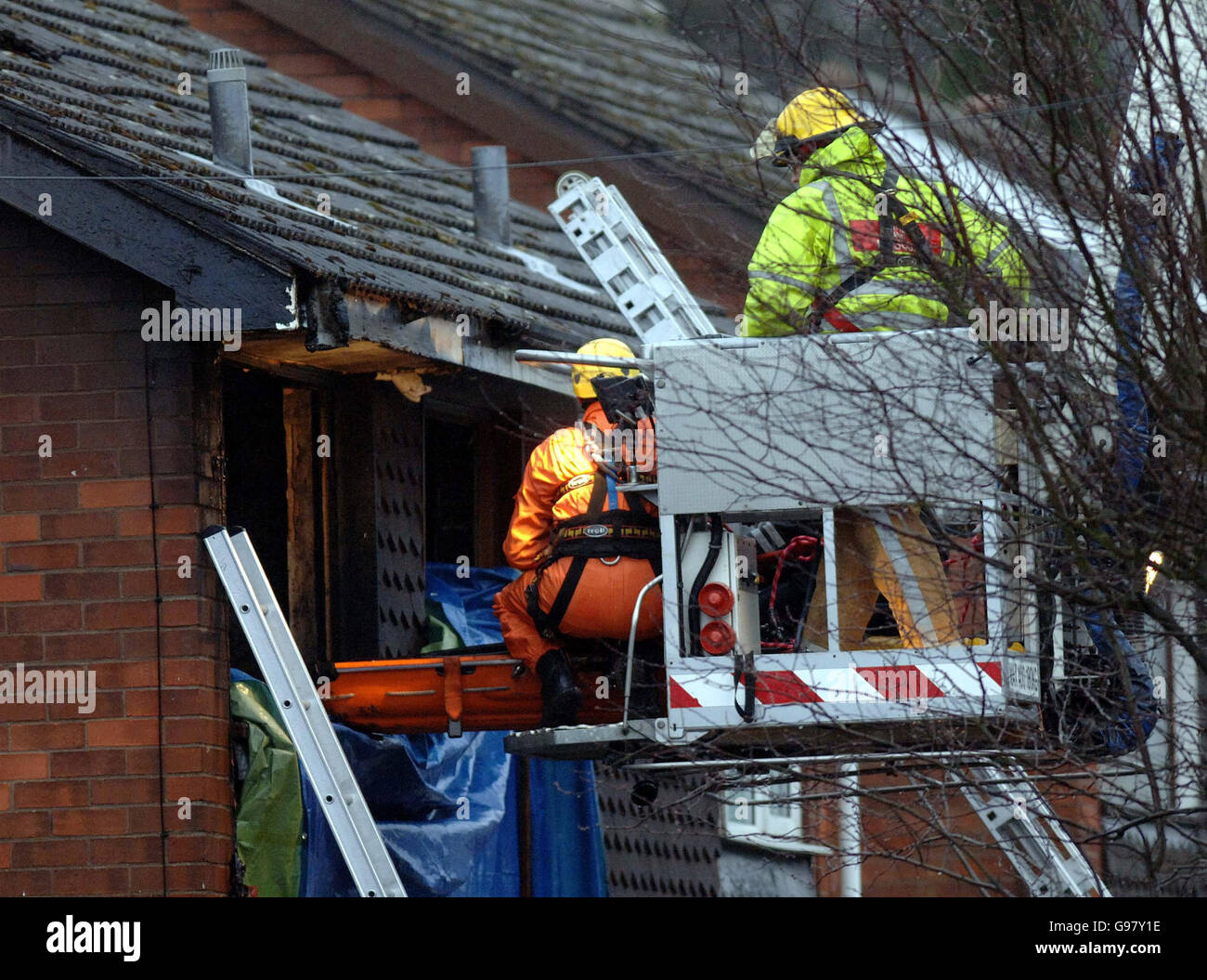 Emergency service personnel use an aerial ladder to work at a house, in ...