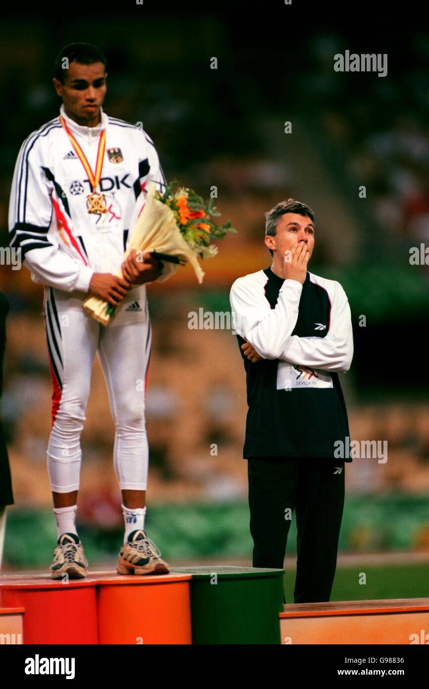 Great Britain's Jonathan Edwards (right) waits to receive his bronze ...