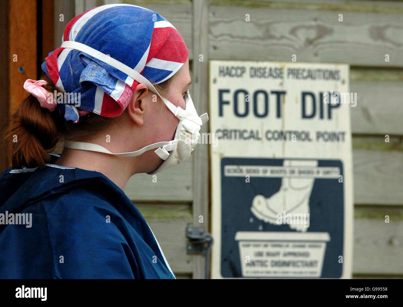 A farm worker walks past a disease prevention sign at Witford Lodge ...