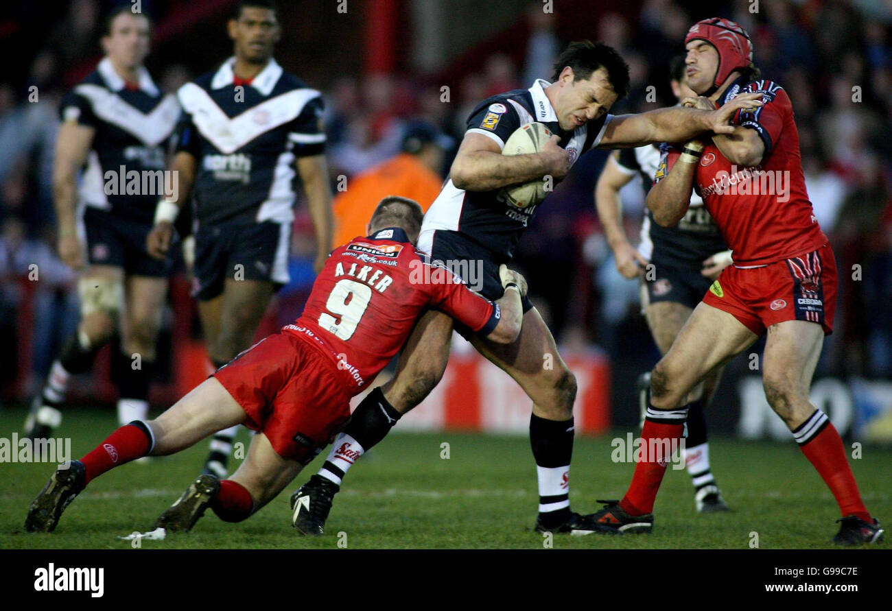 St Helens' Paul Sculthorpe (C) hands off Salford's Simon Baldwin as he ...