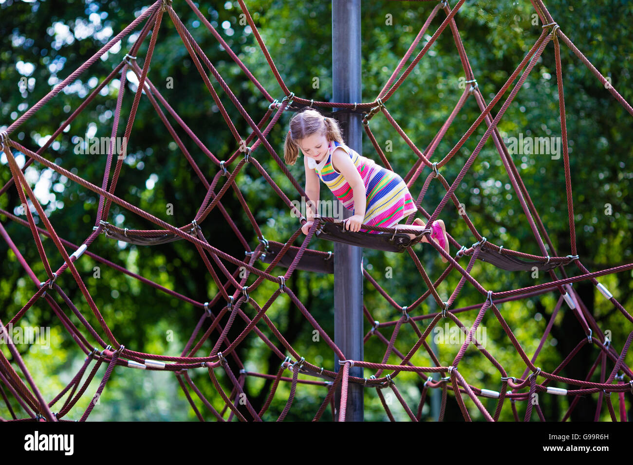 Active little child playing on climbing net and jumping on trampoline ...