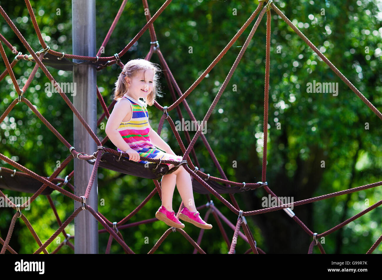Active little child playing on climbing net and jumping on trampoline ...