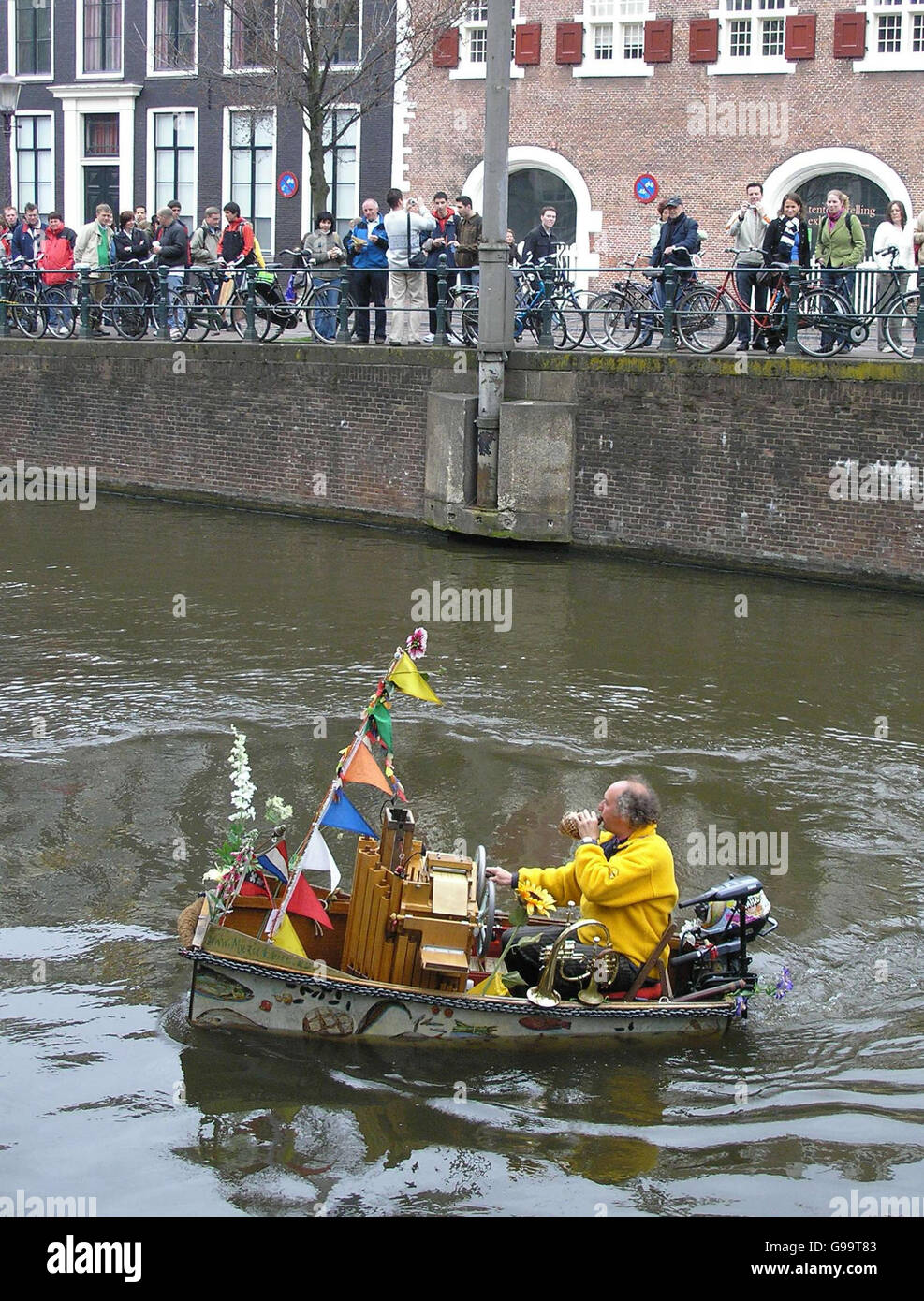 A busker floating on a canal entertains visitors to Amsterdam.. A ...
