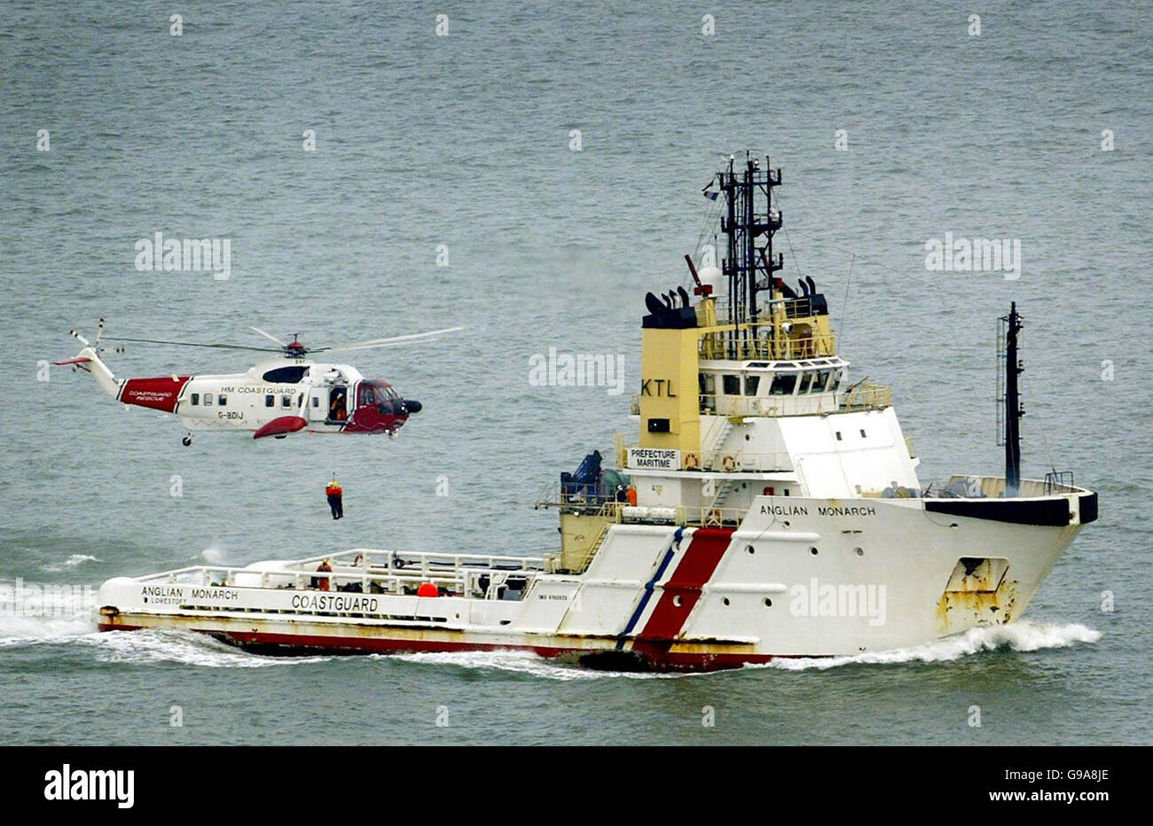 A coast guard helicopter winches a fire crew down onto a ship during a ...