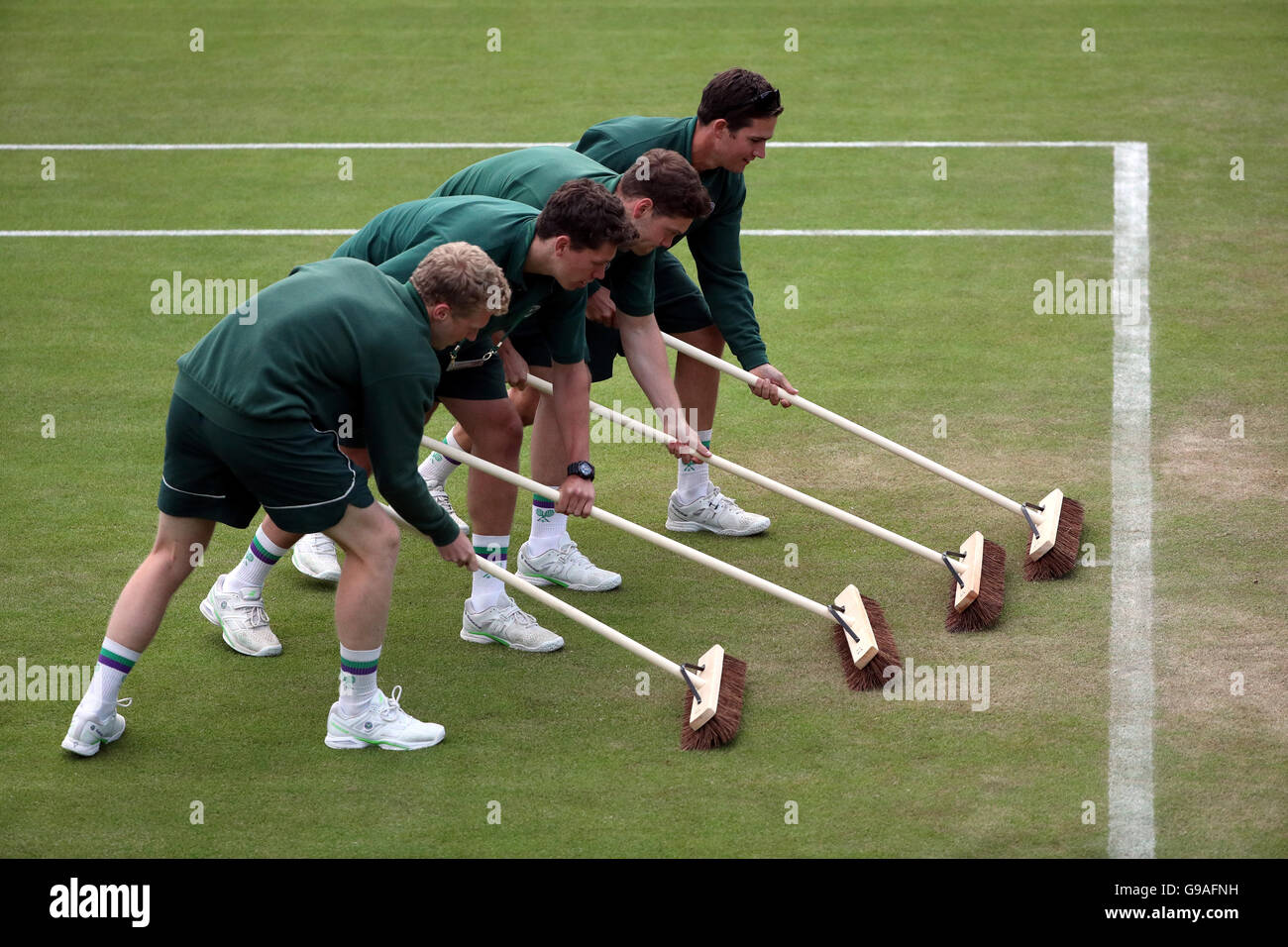 Ground staff sweep the court on day Four of the Wimbledon Championships ...