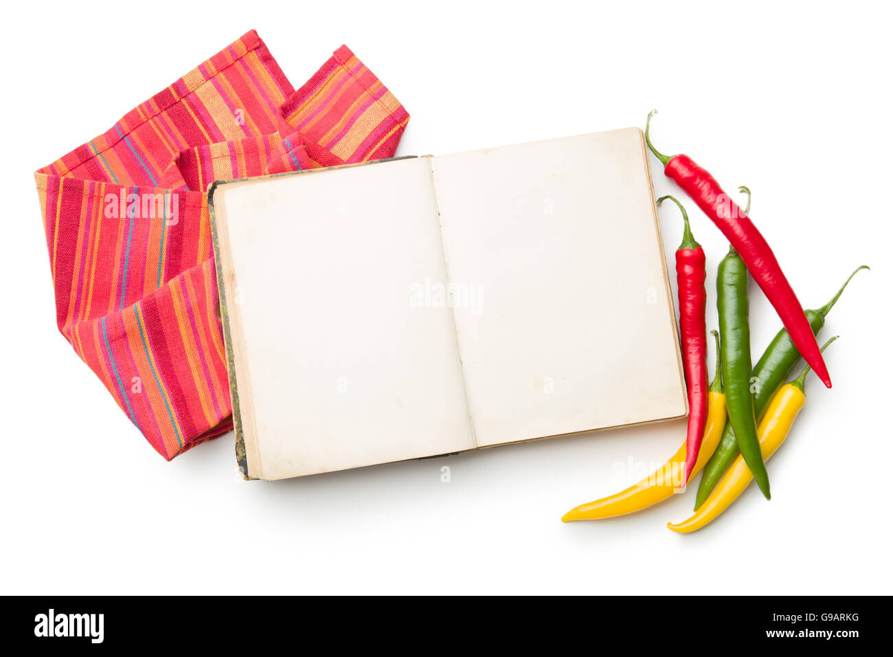 Old cookbook and different colors chilli peppers isolated on white ...