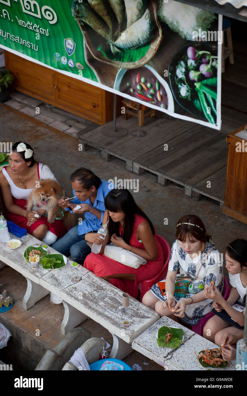 A group of tourists eat grilled seafood at the floating market in ...